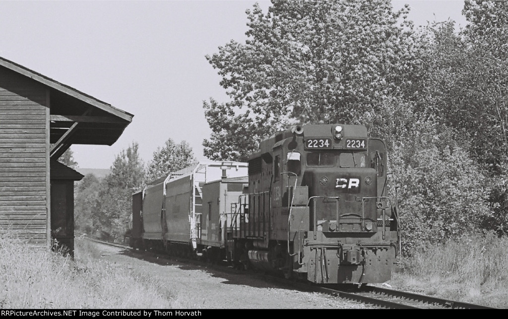 CR 2234 leads its caboose and four freight cars past the depot